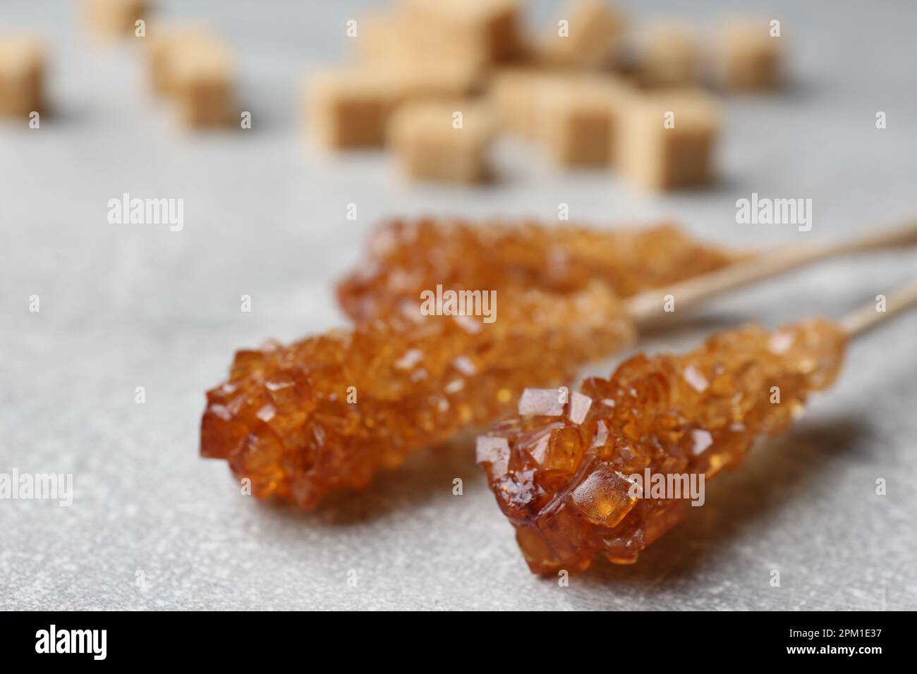 Sticks with sugar crystals on light grey table, closeup. Tasty rock ...