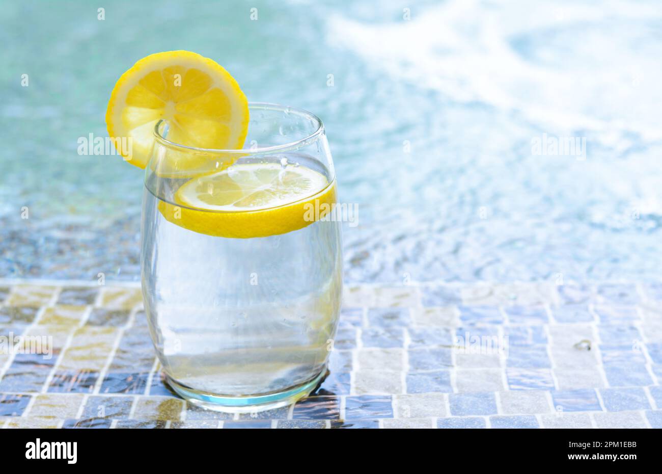 Refreshing water with lemon on edge of swimming pool, space for text ...
