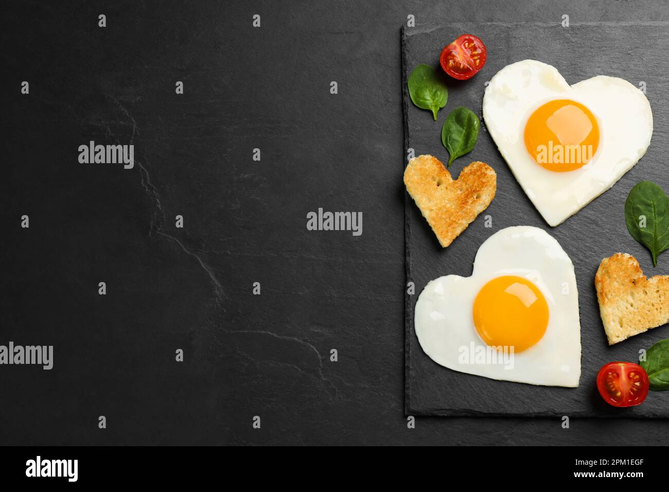 Heart shaped fried eggs and toasts on black table, top view. Space for text Stock Photo - Alamy