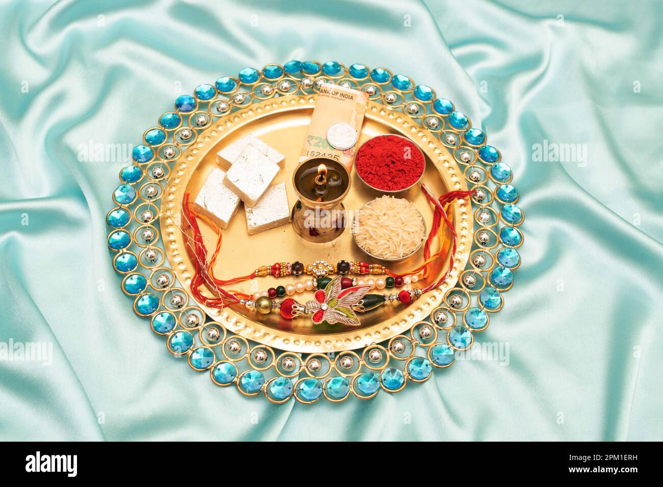 Rakhi with indian sweets and roli in pooja thali on blue background ...