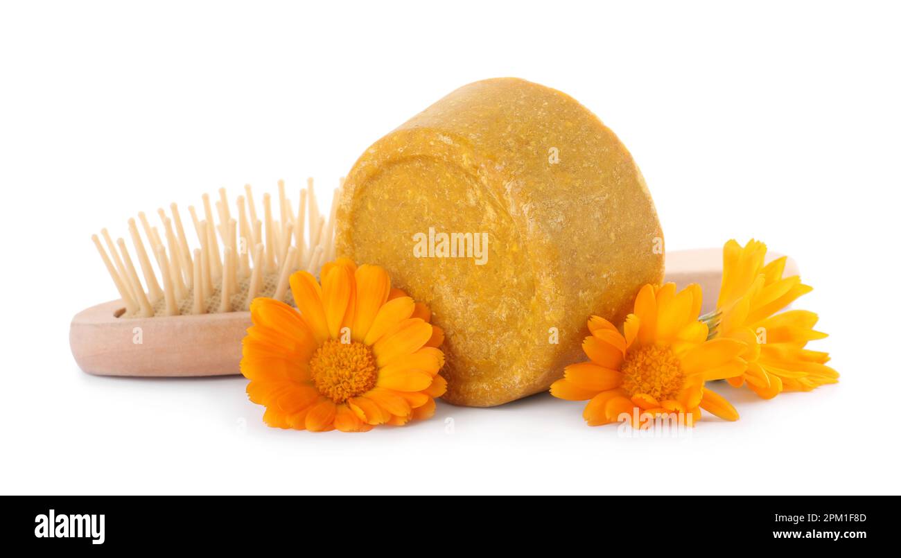 Yellow solid shampoo bar, hairbrush and flowers on white background ...