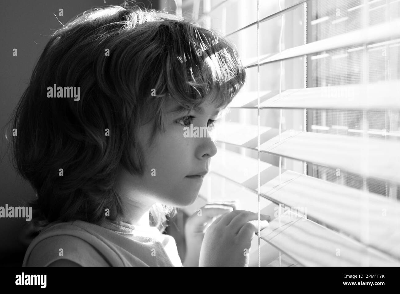 COVID-19 Lockdown. Depressed lonely kid looking through window ...
