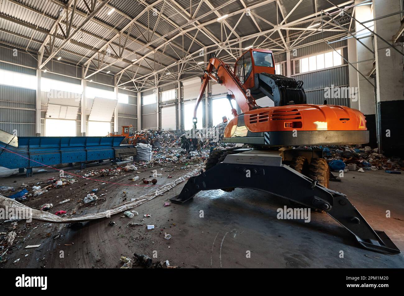 Excavator grabs trash in warehouse of waste processing plant Stock ...
