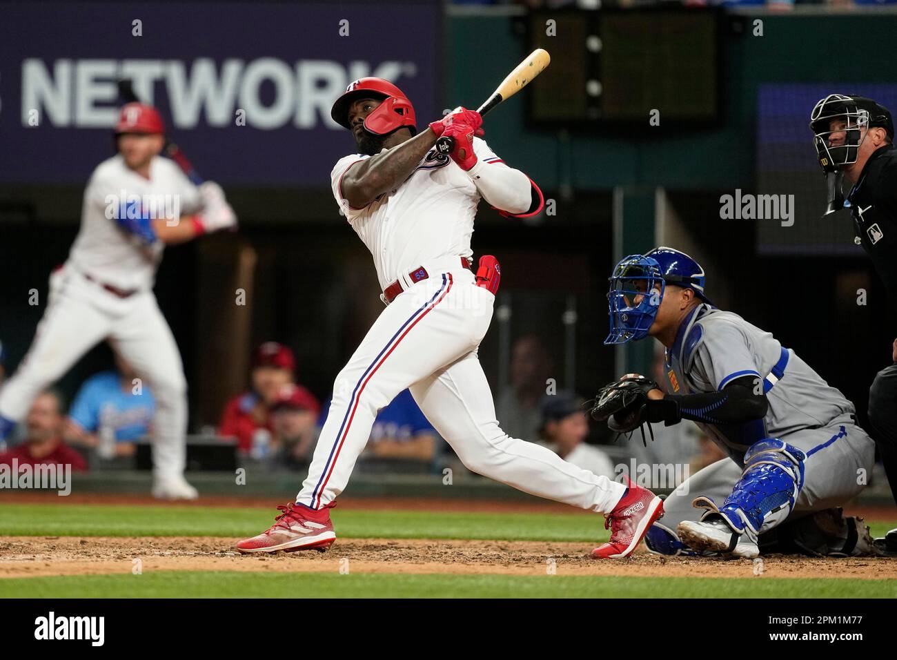 Texas Rangers' Adolis Garcia, front left, follows through on a grand ...