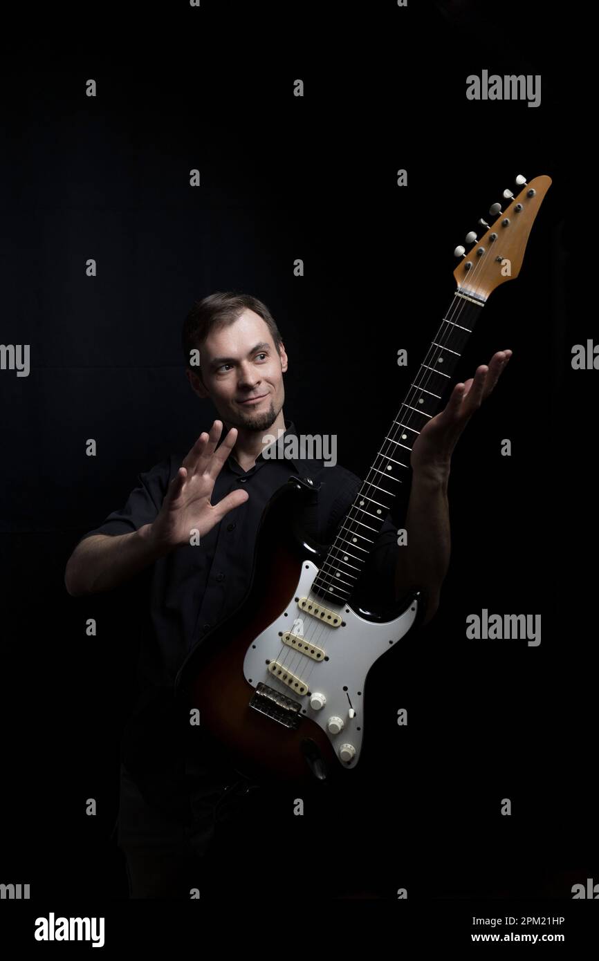 The guitarist masterfully controls the electric guitar, studio portrait ...
