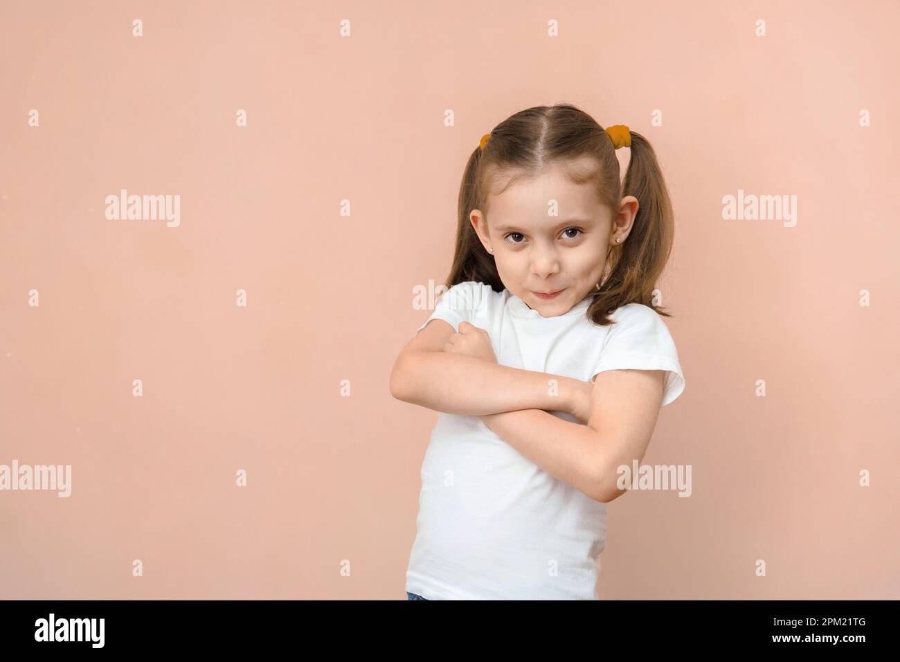 A slightly offended Caucasian girl of 7 years old crossed her arms over ...