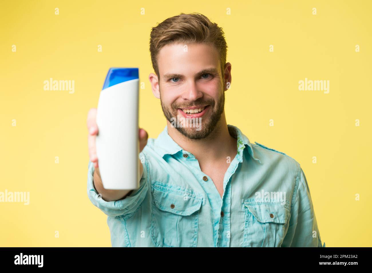 selective focus of man hold shampoo cosmetics in studio background ...