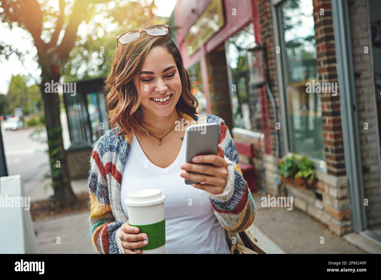 Updating her status on the go. a happy young woman using her cellphone ...