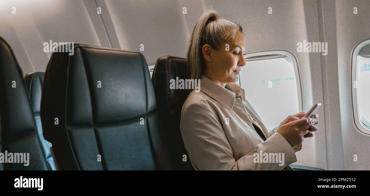 Beautiful Asian woman passenger sitting in the airplane and use phone during boarding Stock ...