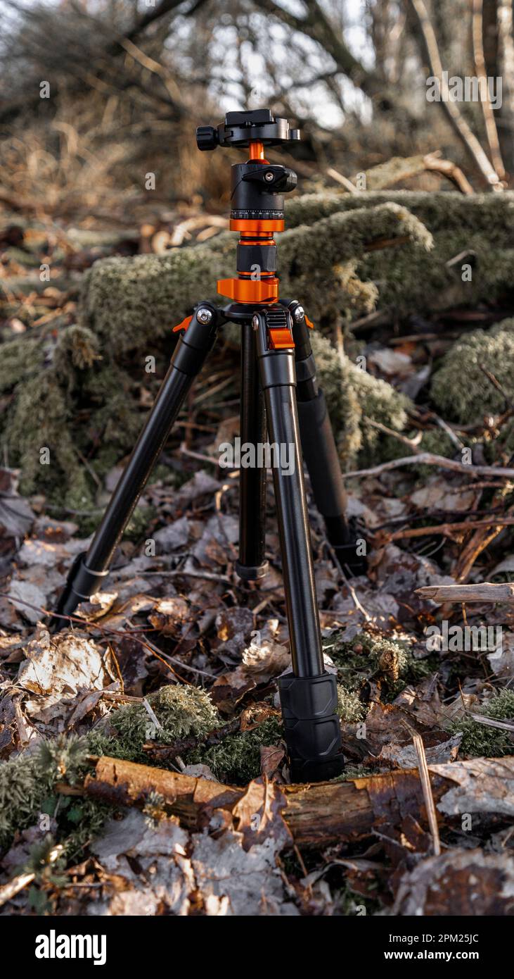 A three-legged camera stand propped up on the ground against a backdrop ...