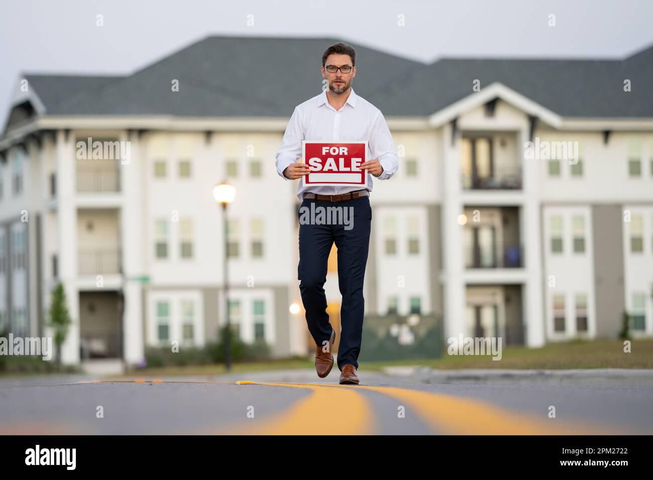 Handsome real estate agent holding banner house for sale. House with ...