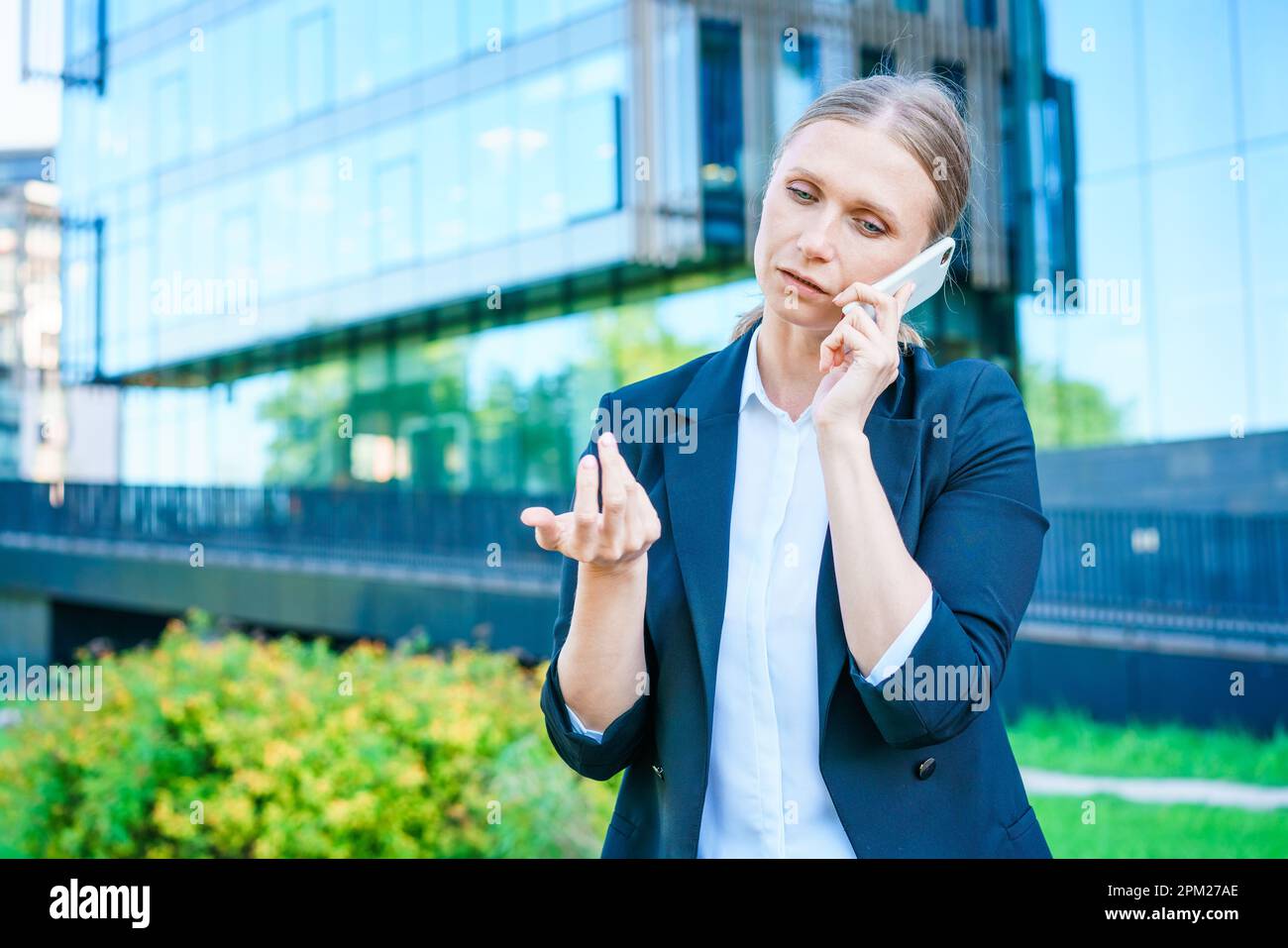 Successful female banker using smart phone outdoors while standing near ...