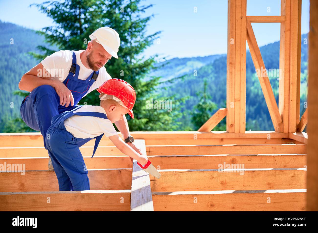 Father with toddler son building wooden frame house. Man teaching the ...
