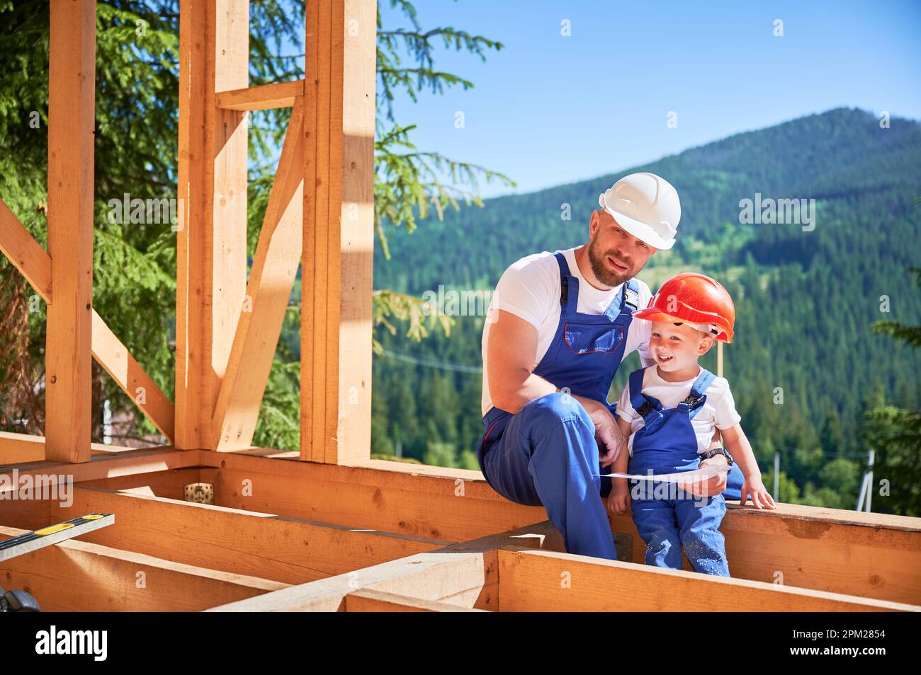 Father with toddler son building wooden frame house in the mountains ...