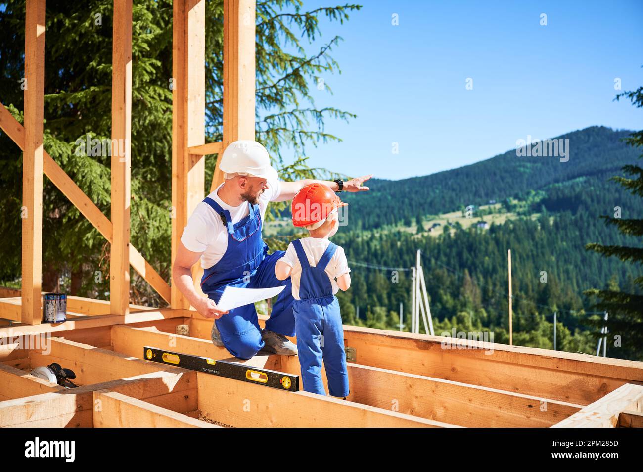 Father with toddler son building wooden frame house. Male builder ...
