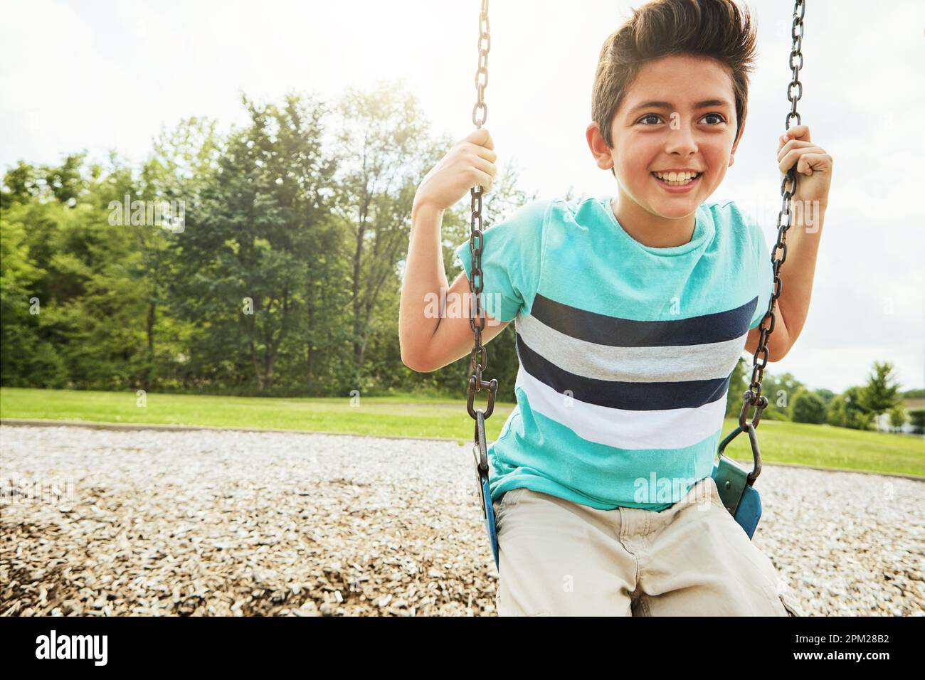 The swing is his throne. a young boy playing on a swing at the park ...