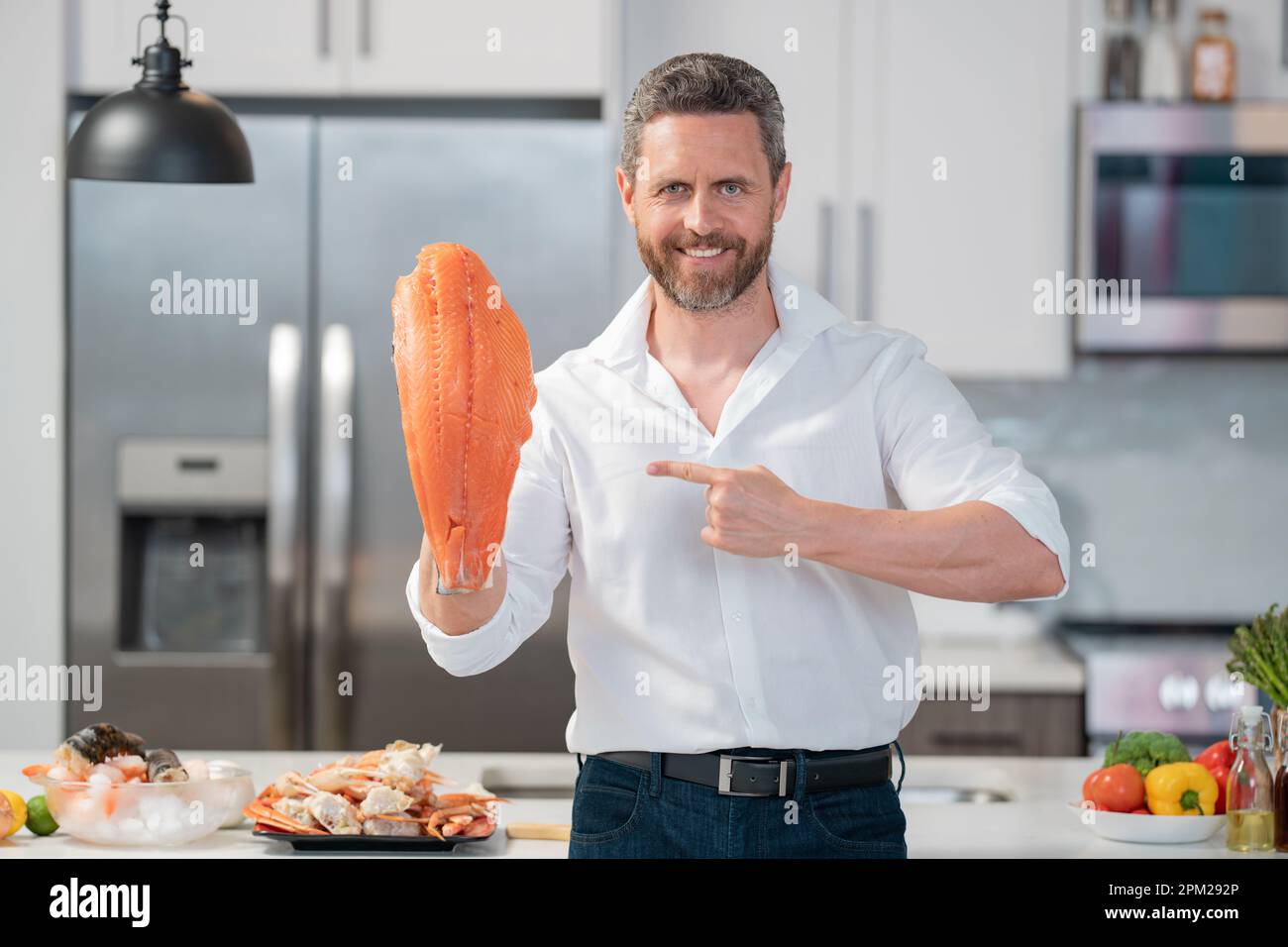 Chef cook in shirt cooking raw fish salmon fillet in the kitchen ...