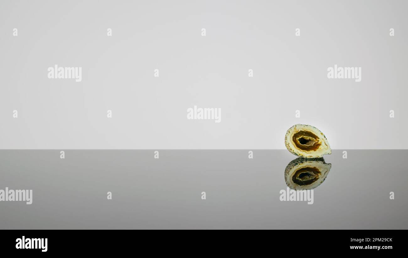 A geode rock crystal with its reflection against a grey background ...