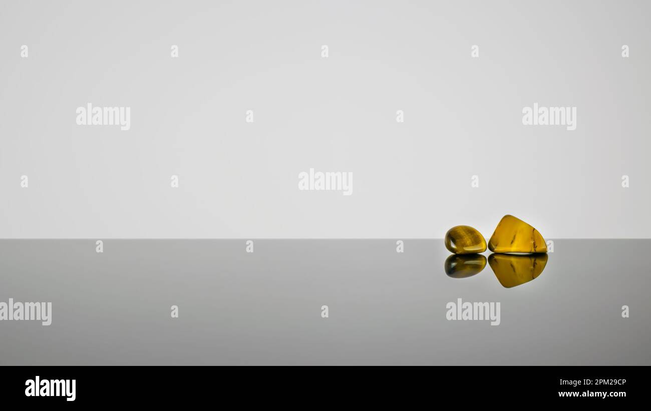 The amber rock crystals with their reflection against a grey background ...