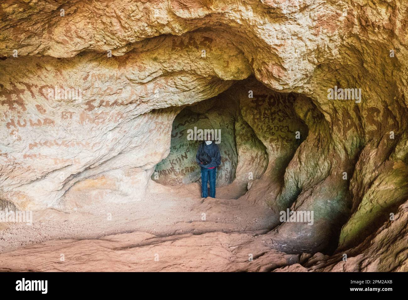 Rear view of a man inside a cave against a waterfall in Sipi Falls ...