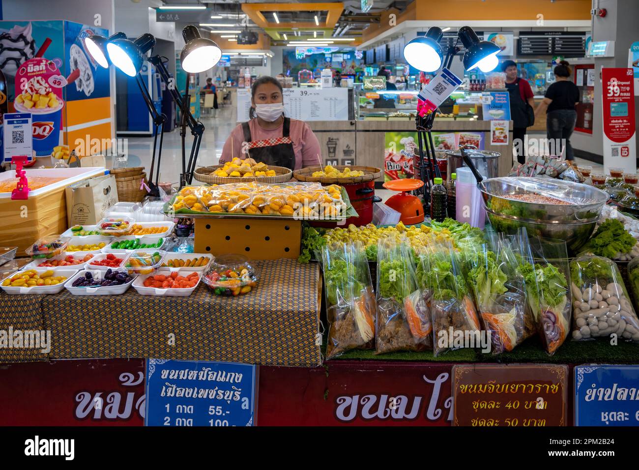 A young woman stand behind a food stand in a market. Tak, Thailand ...