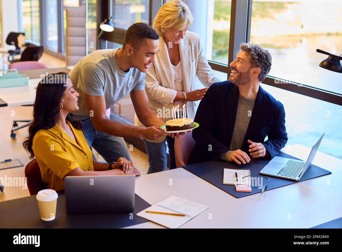 Staff Celebrating Birthday Of Male Colleague At Desk In Office With ...