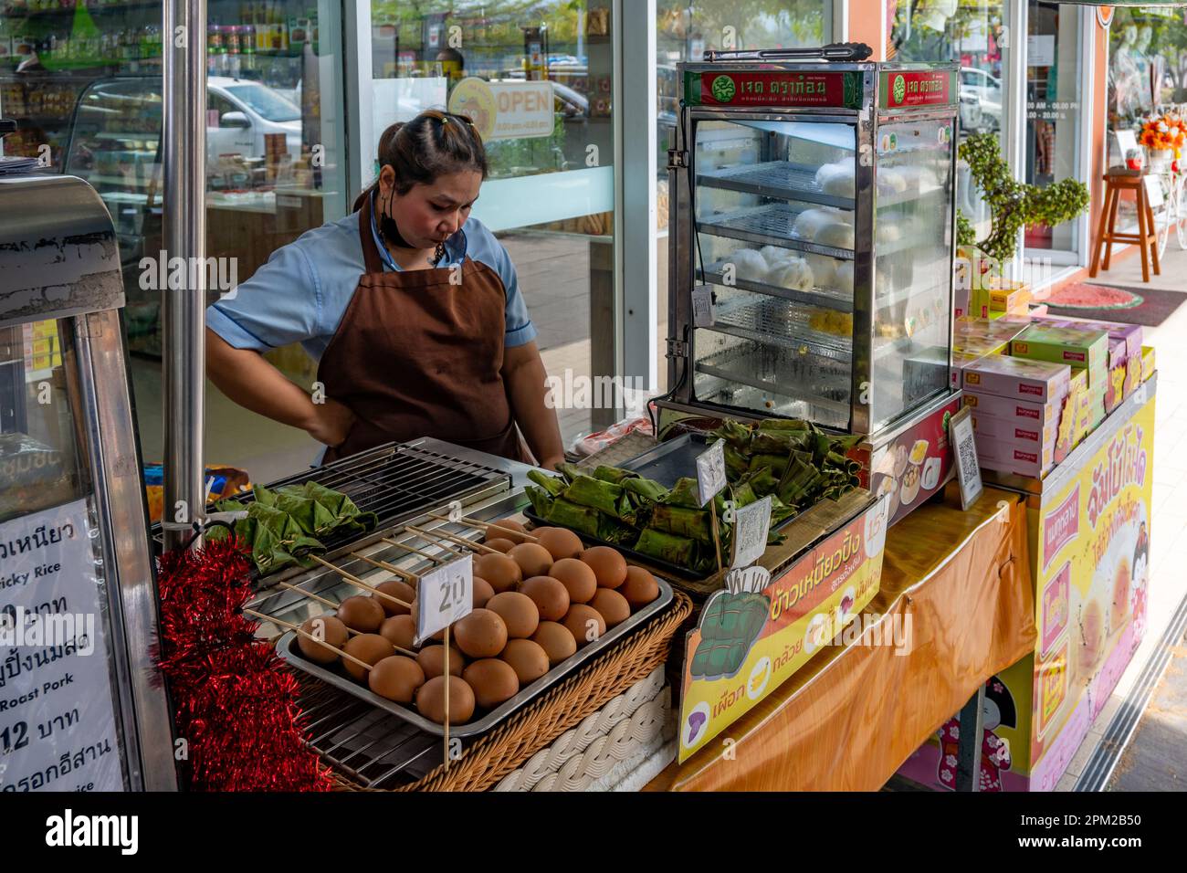 A young woman stand behind a food stand with varieties of snacks. Tak ...