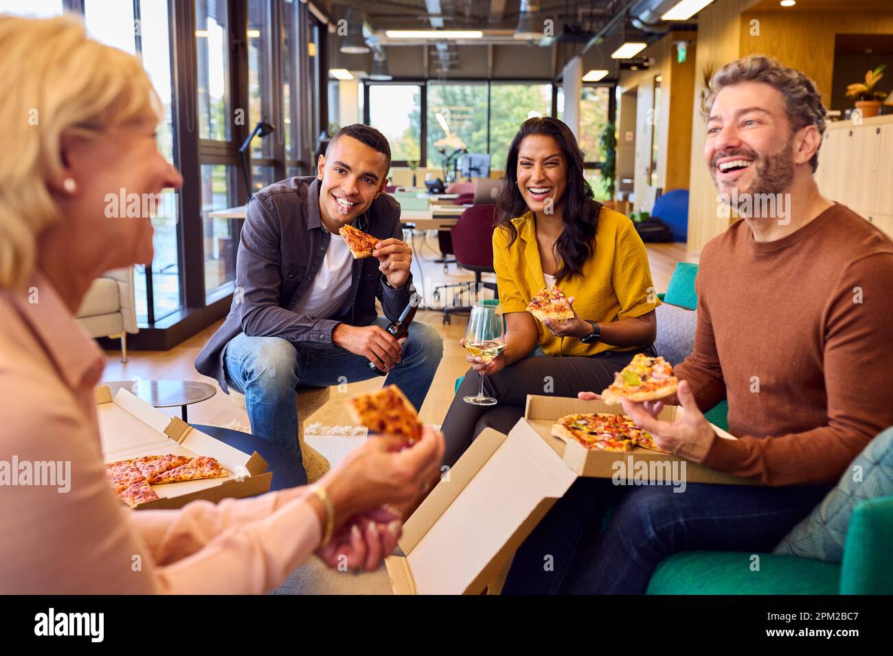 Staff Meeting And Eating Takeaway Pizza In Office At The End Of Working ...