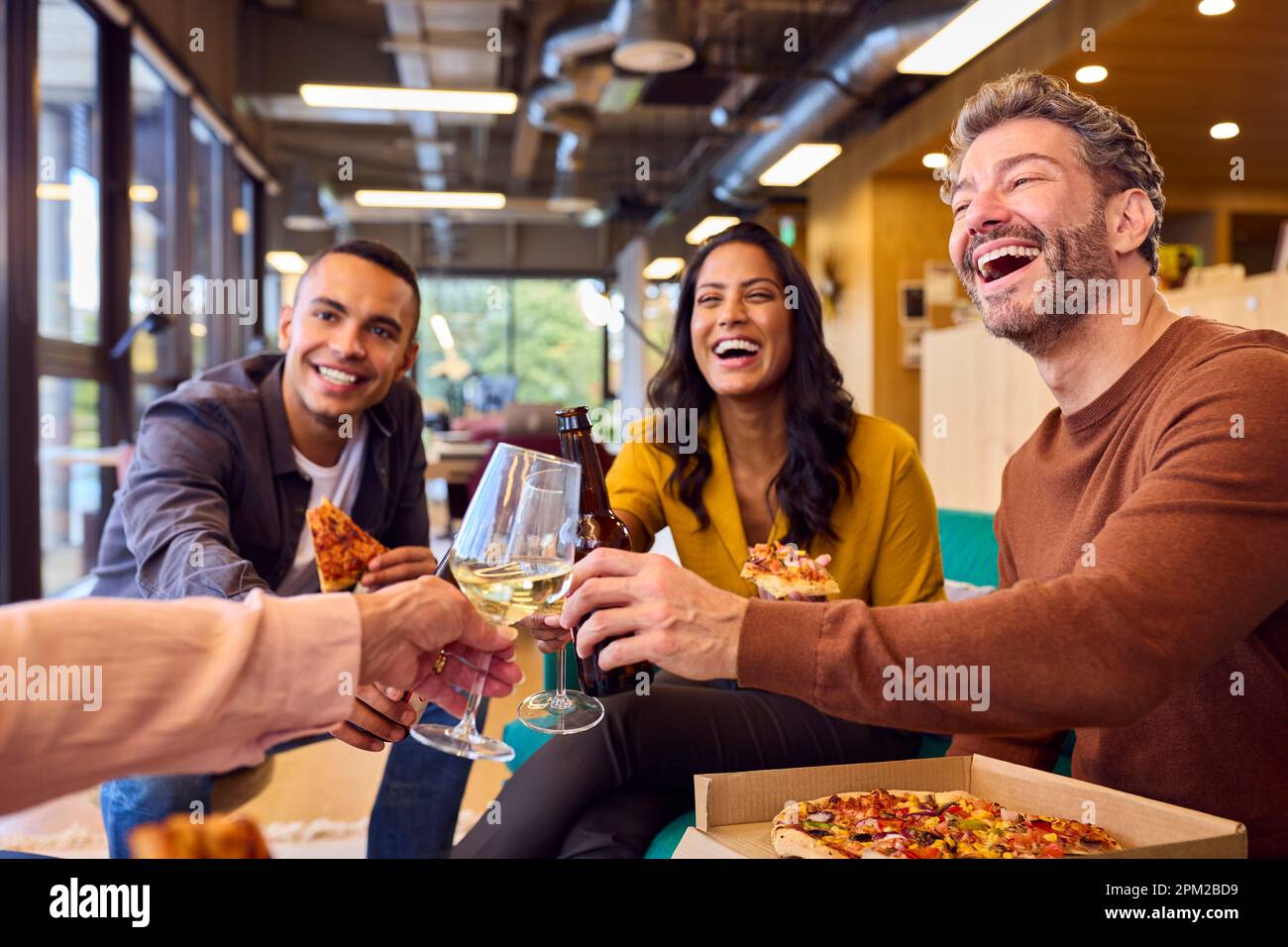 Staff At Informal Meeting In Office With Takeaway Pizza And Drinks ...