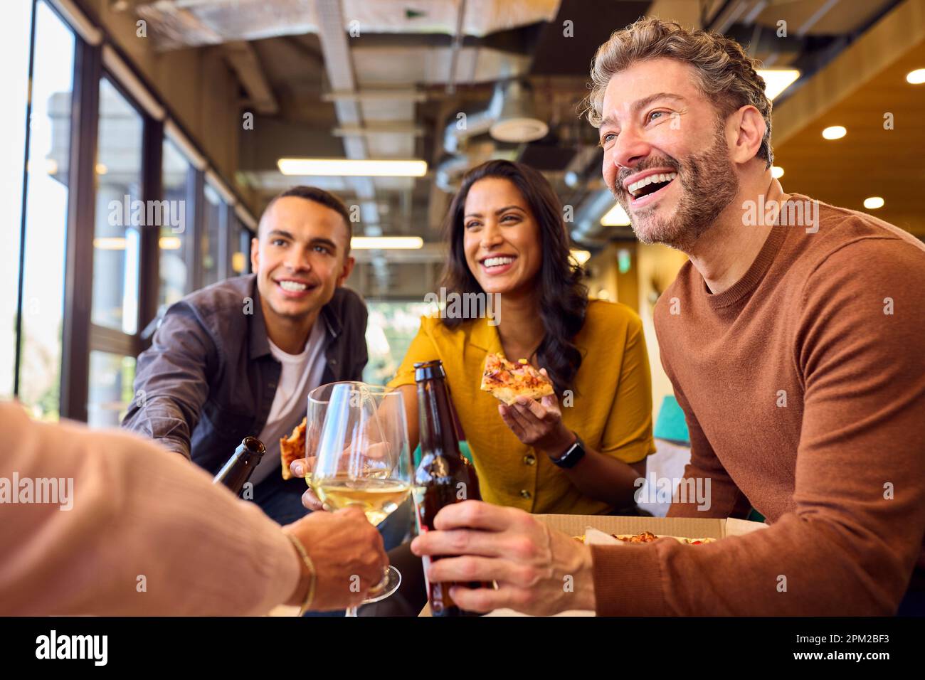 Staff At Informal Meeting In Office With Takeaway Pizza And Drinks ...