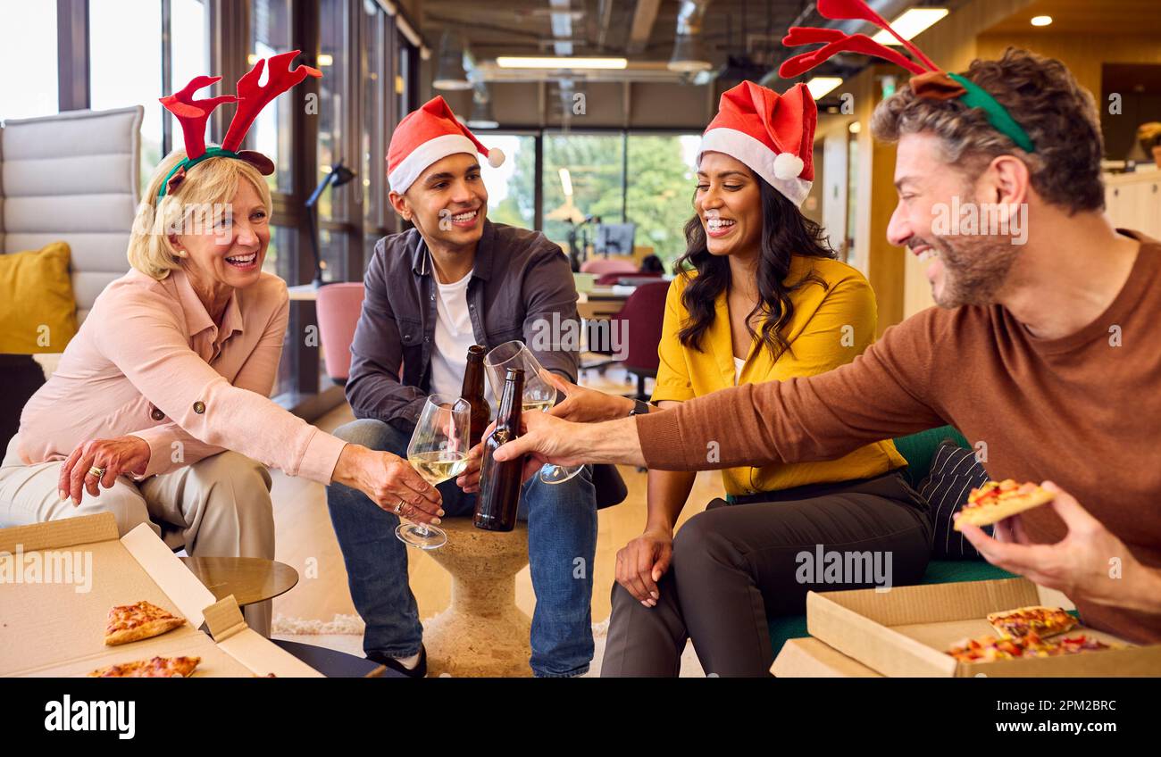 Staff Celebrating At Christmas Party With Meal And Drinks In Office ...