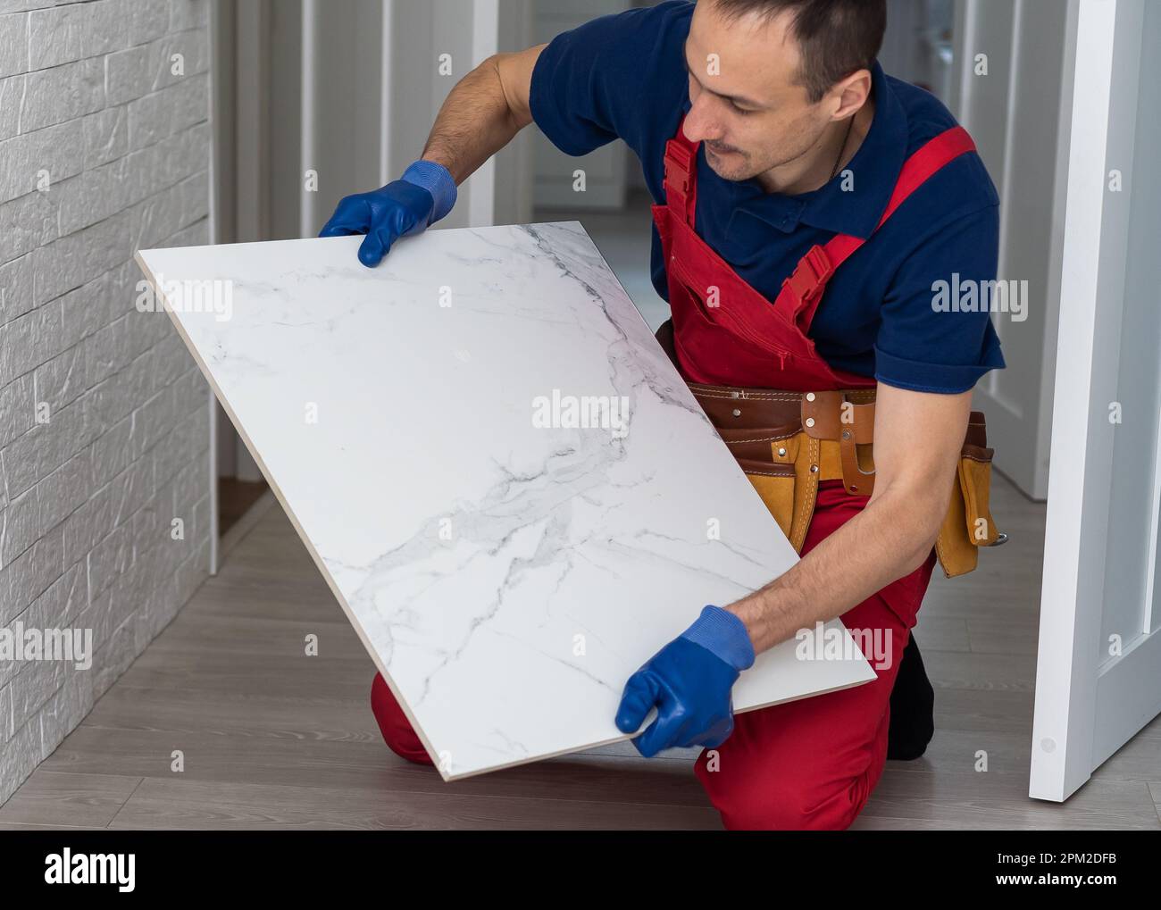 A male construction worker installs a large ceramic tile Stock Photo ...