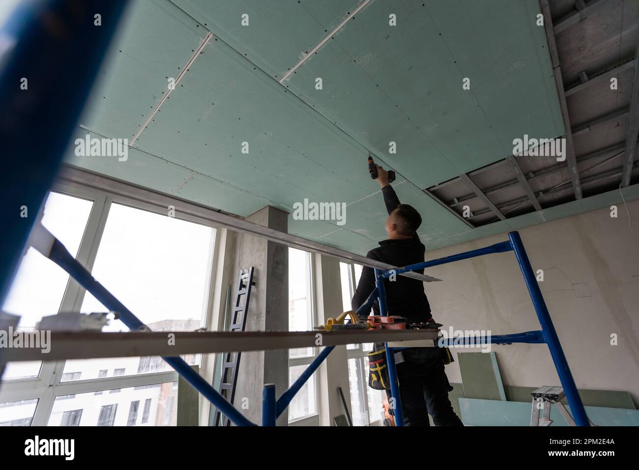 Construction worker assemble a suspended ceiling with drywall and ...
