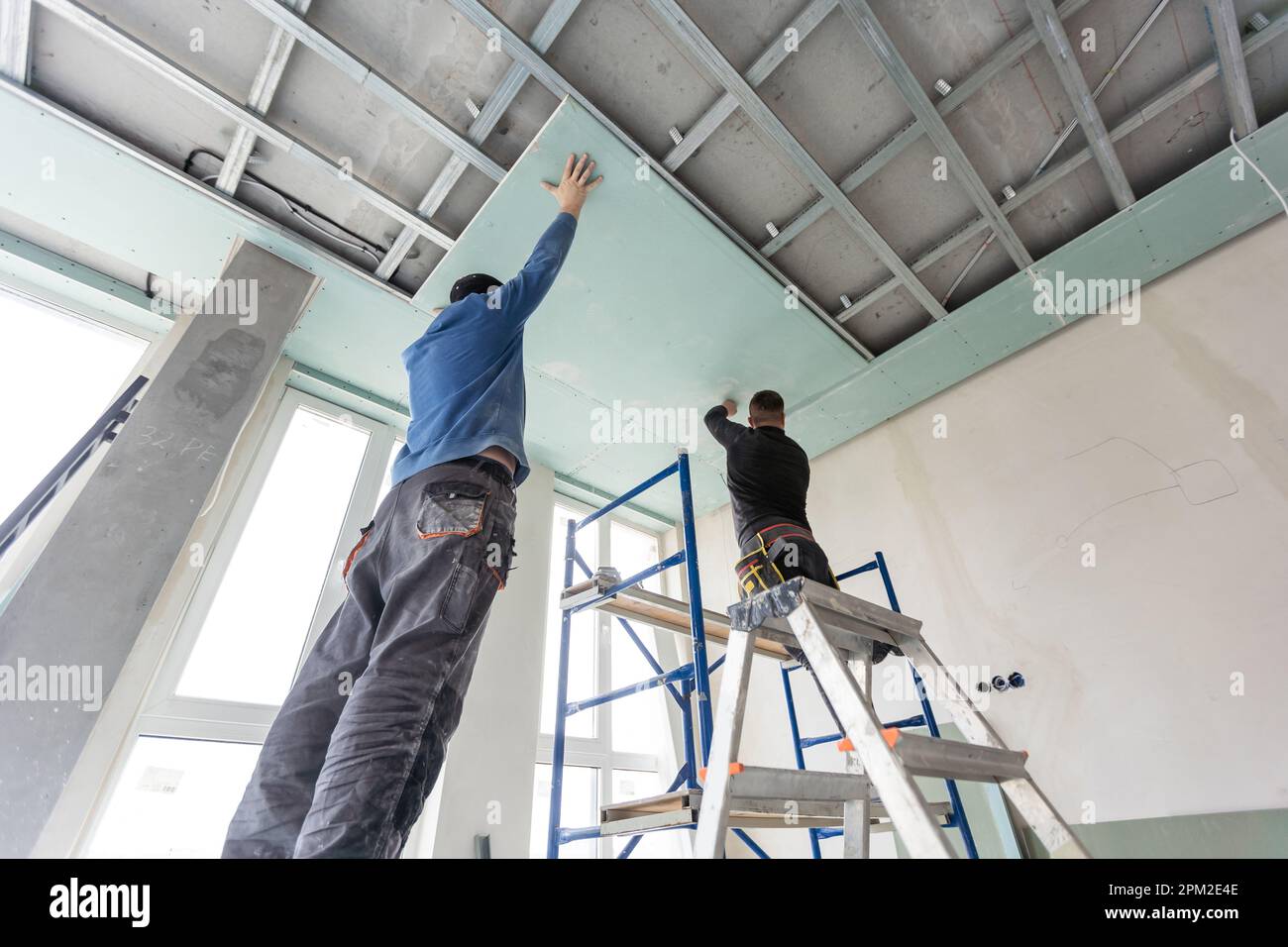 Two man help for ceiling house construction Stock Photo - Alamy