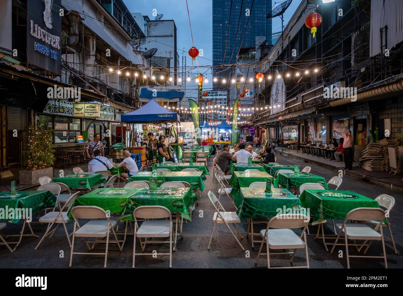 Tables set up on the street at a night market at downtown Bangkok ...
