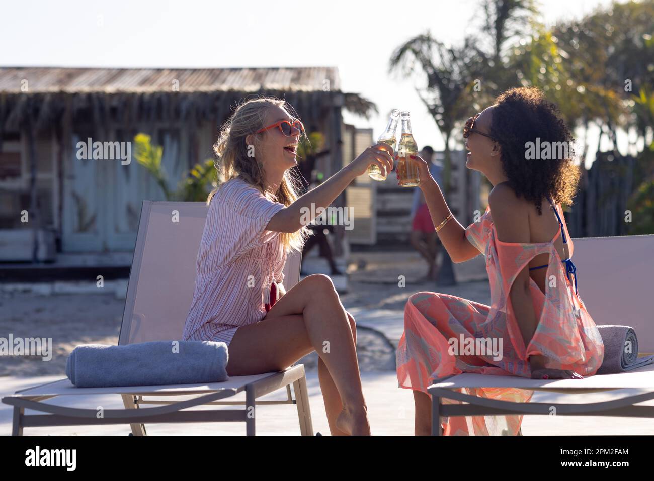 Happy diverse female friends having party by swimming pool, sitting on ...
