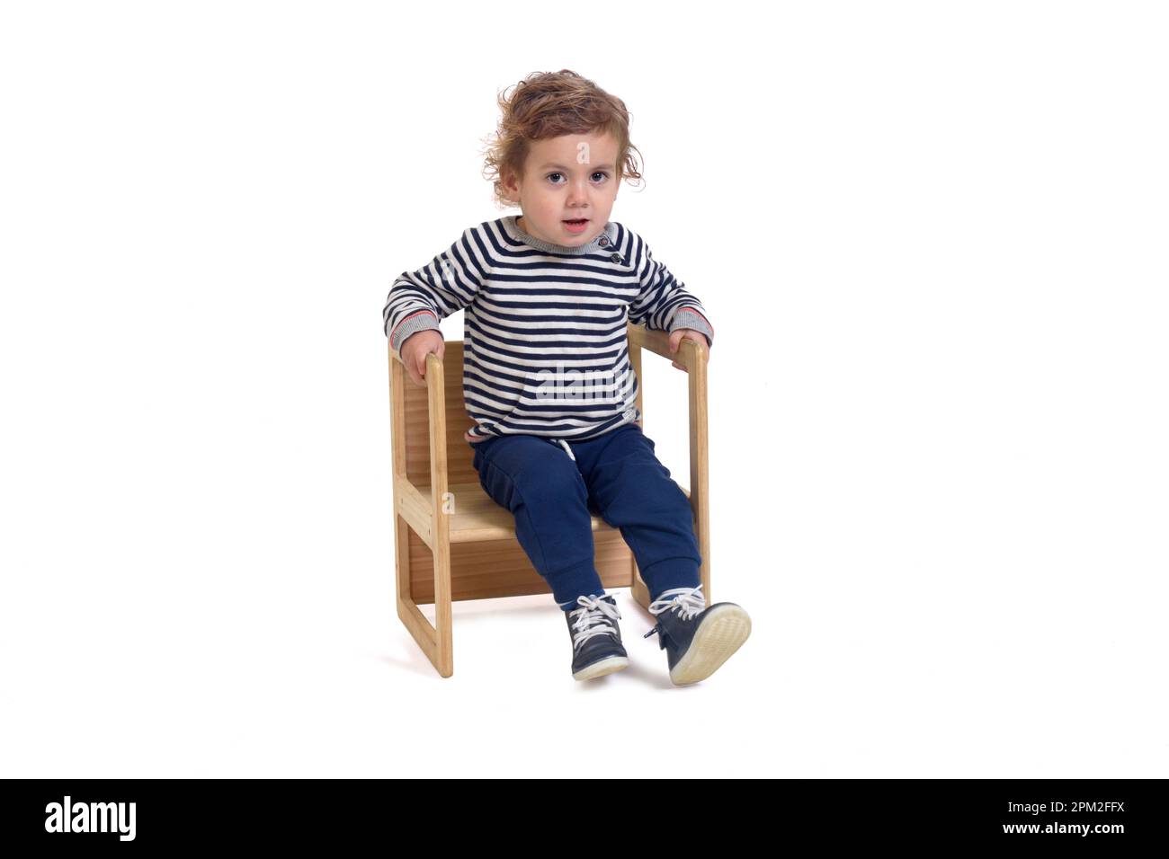 front view of a baby boy sitting on chair and looking at camera on ...