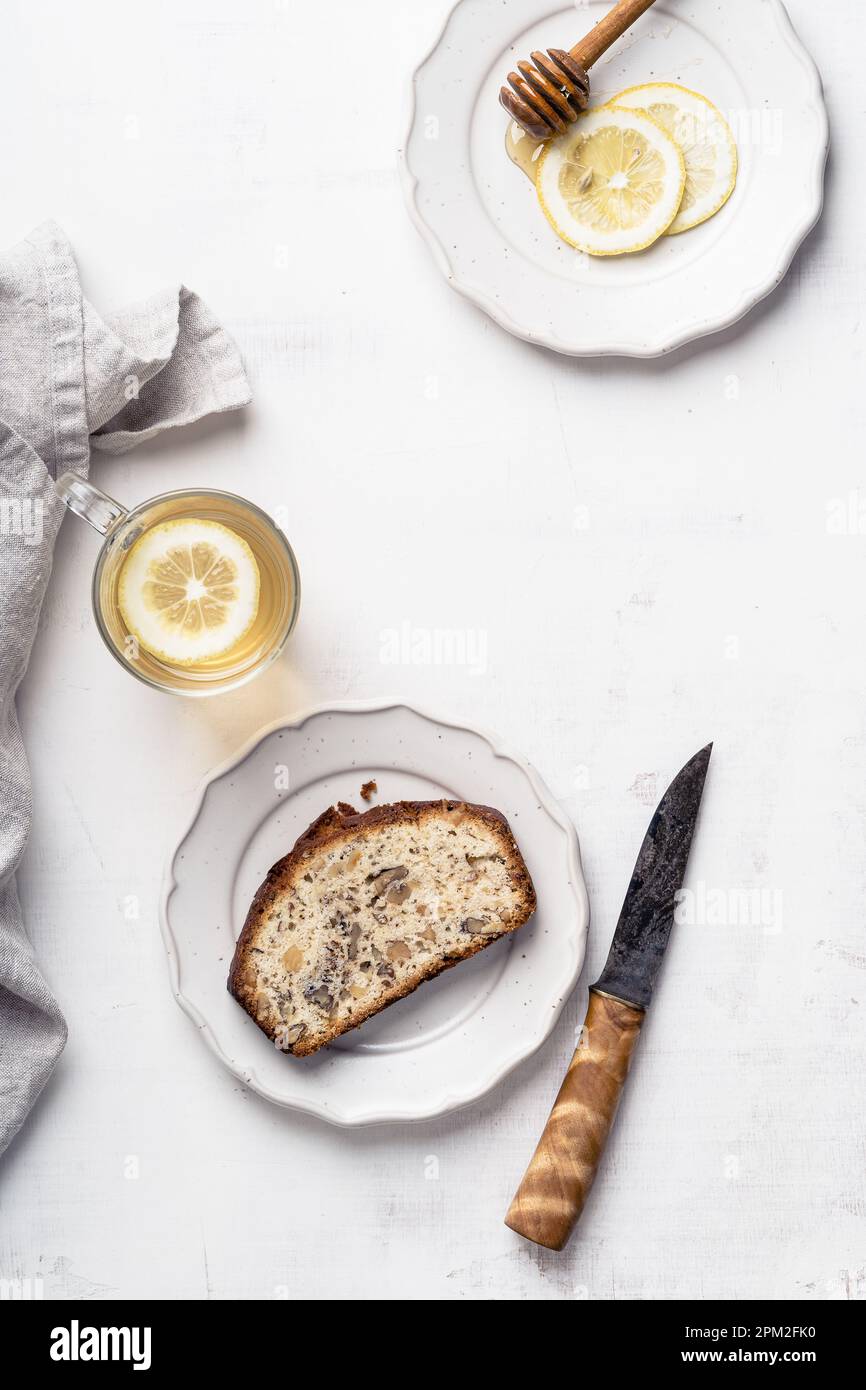 Slice of cake bread with walnuts and hot tea with lemon slice and honey ...