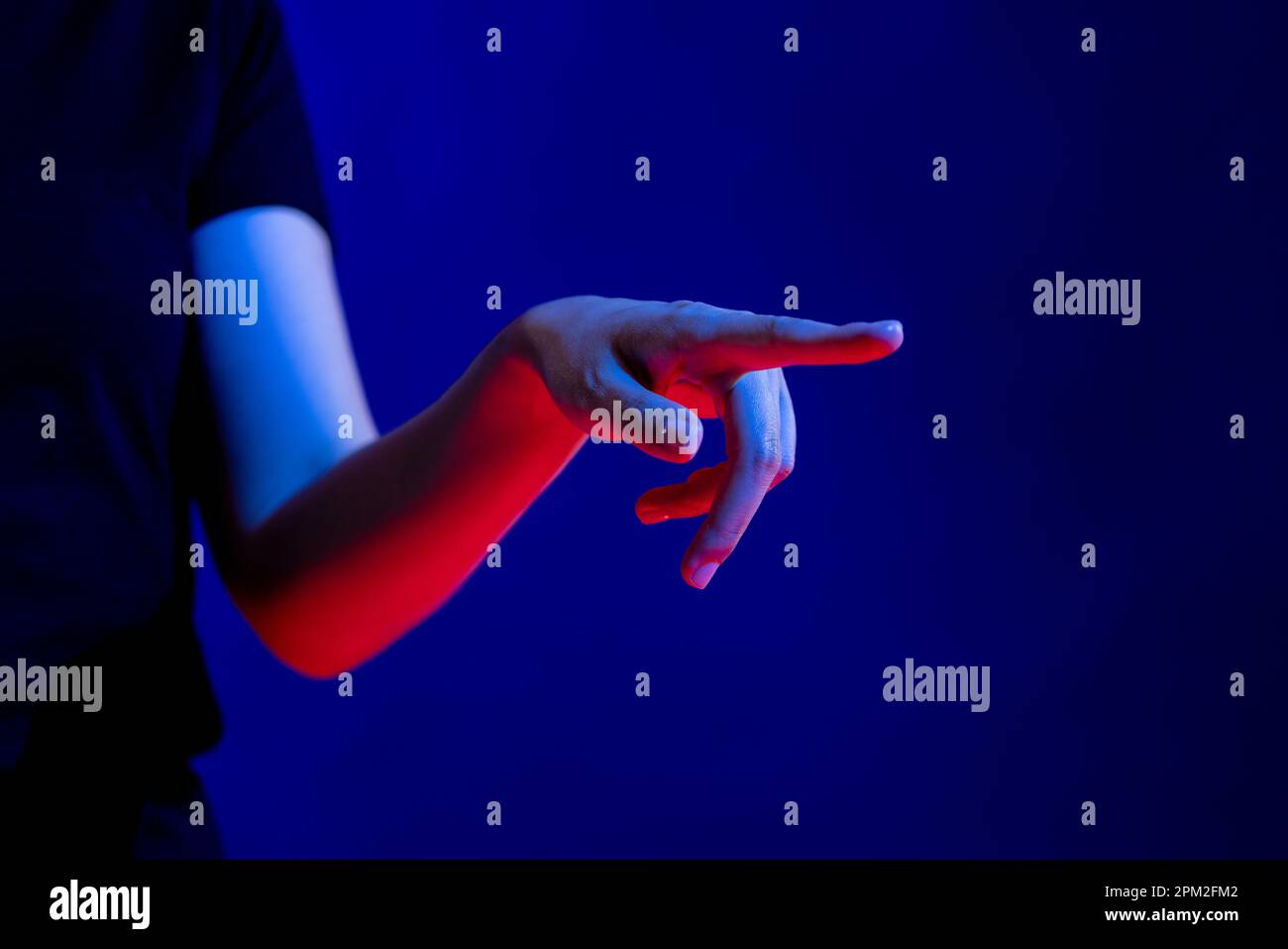 Exposed hand pointing finger in studio with blue light with copy space ...