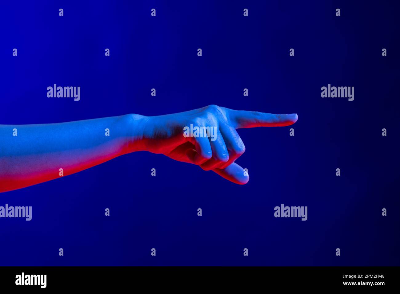 Exposed hand pointing finger in studio with blue light with copy space ...