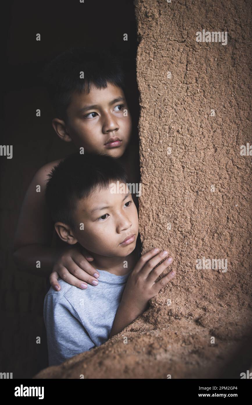 Closeuptwo poor children peeking out of a dilapidated house, Concept of assistance to the poor ...