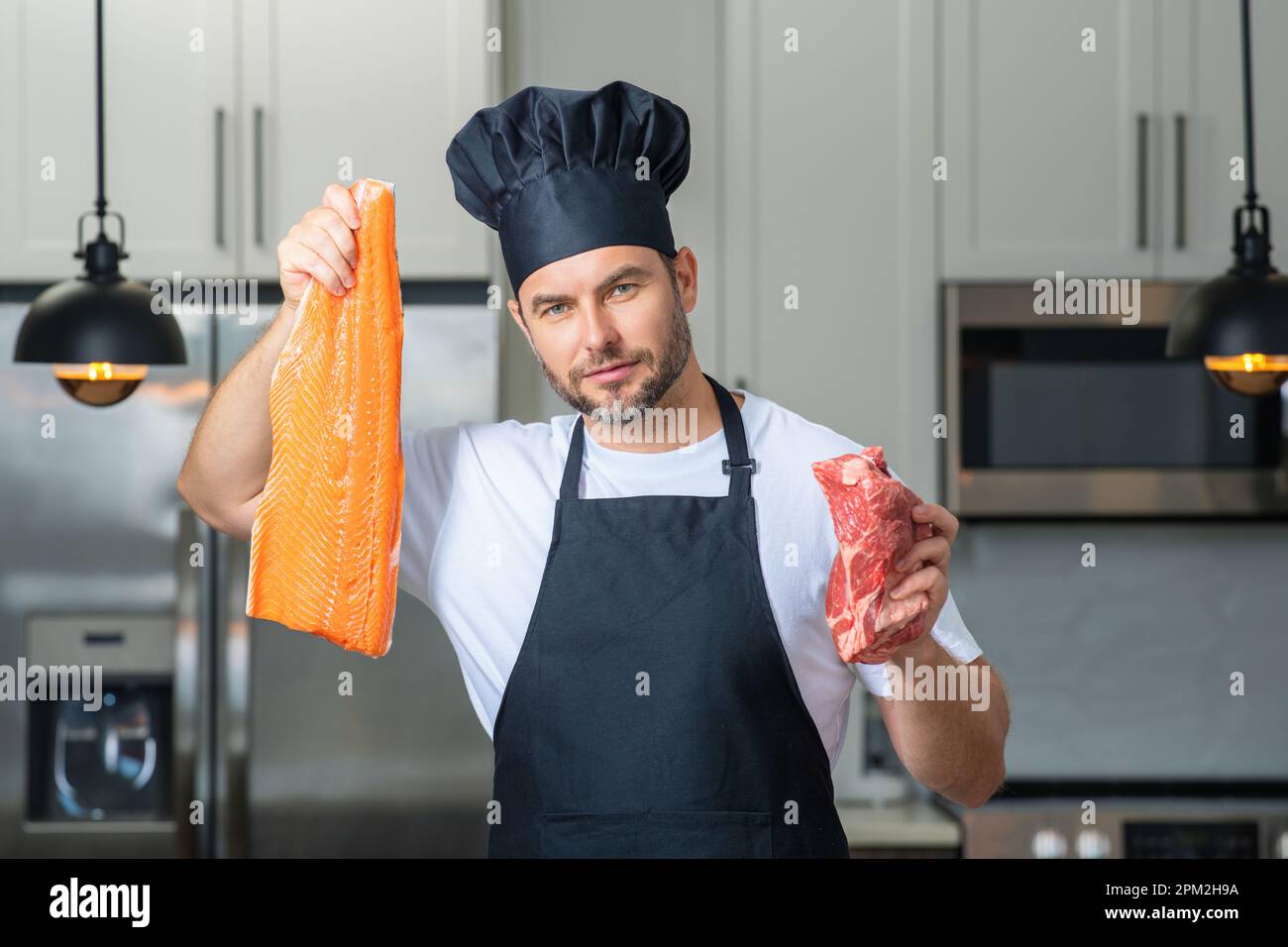 Man chef cooker hold fish and meat, salmon and beef. Male chef in chefs ...