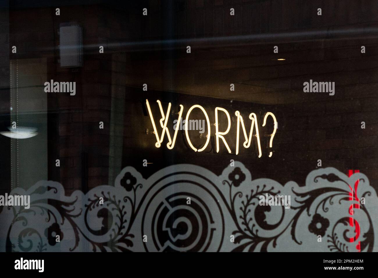 A yellow neon sign forms the word Worm followed by a question mark ...