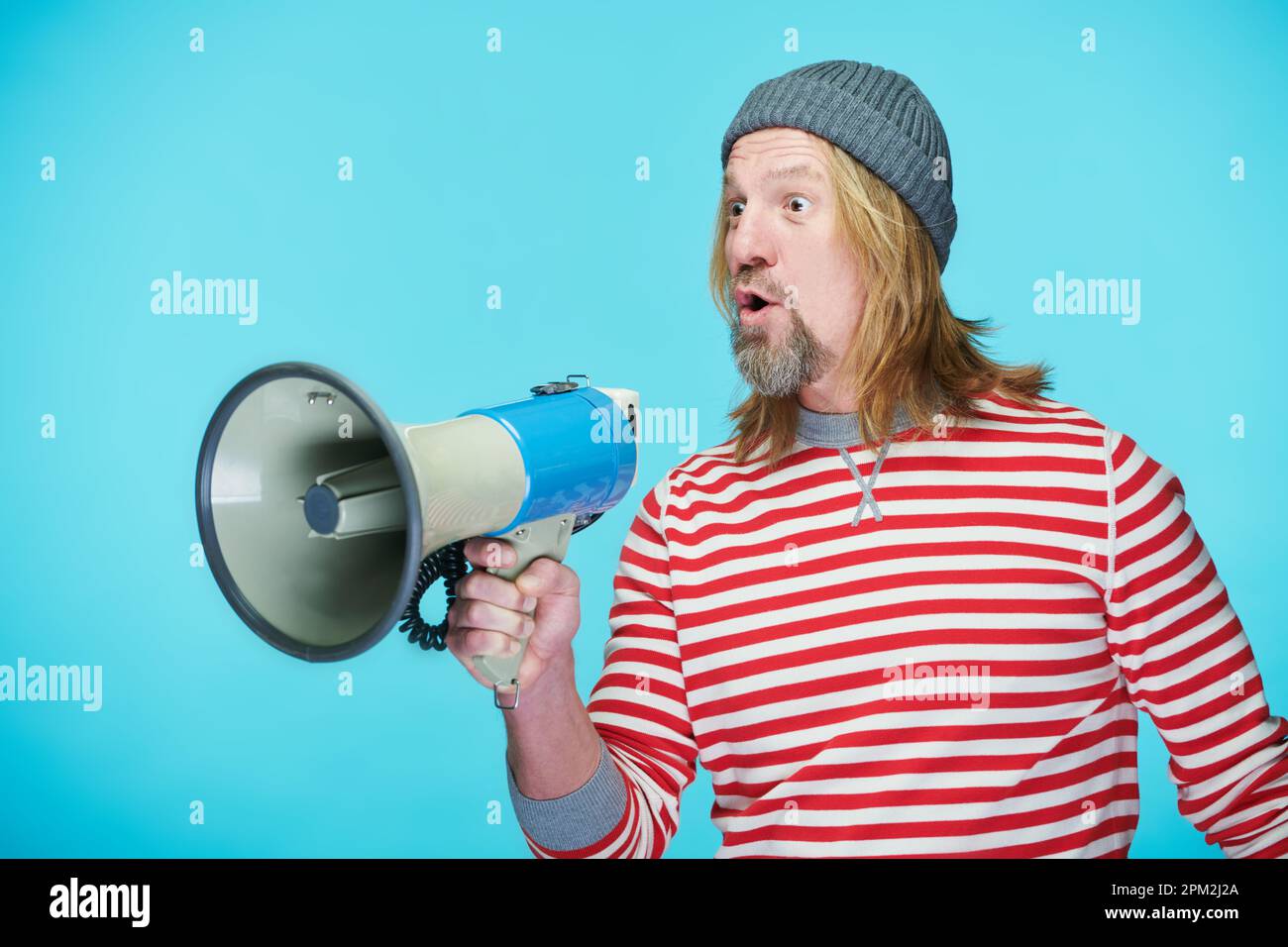 Stylish mature man announcing information in bullhorn standing against ...