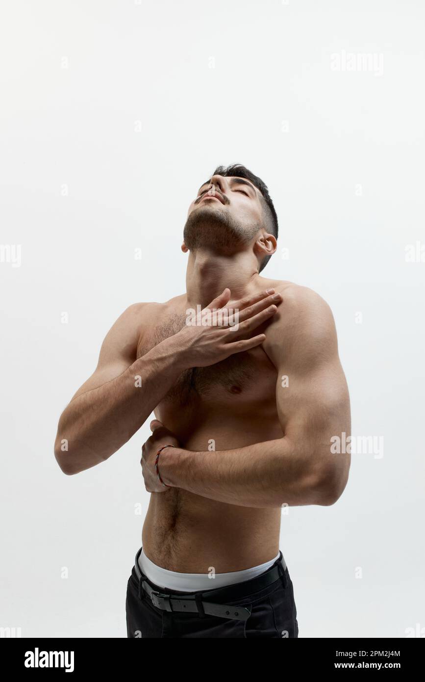 Shot of one attractive muscular man touching his body and looking up ...