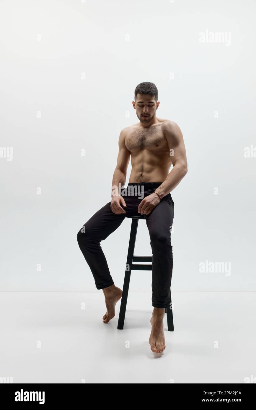 Handsome stylish young man wearing black jeans posing over white studio ...