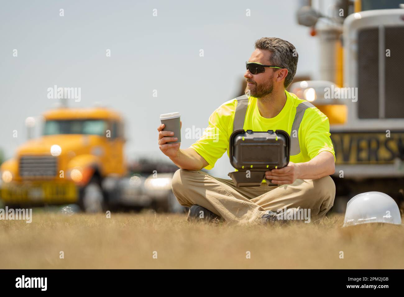 Builder with lunch box and cup of coffee rest. Construction man with ...