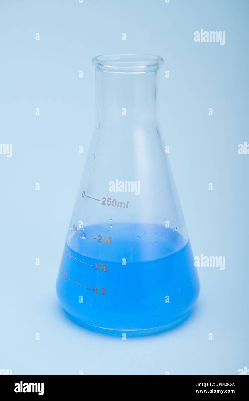 Still life with graduated flat bottomed lab flask with blue chemical ...