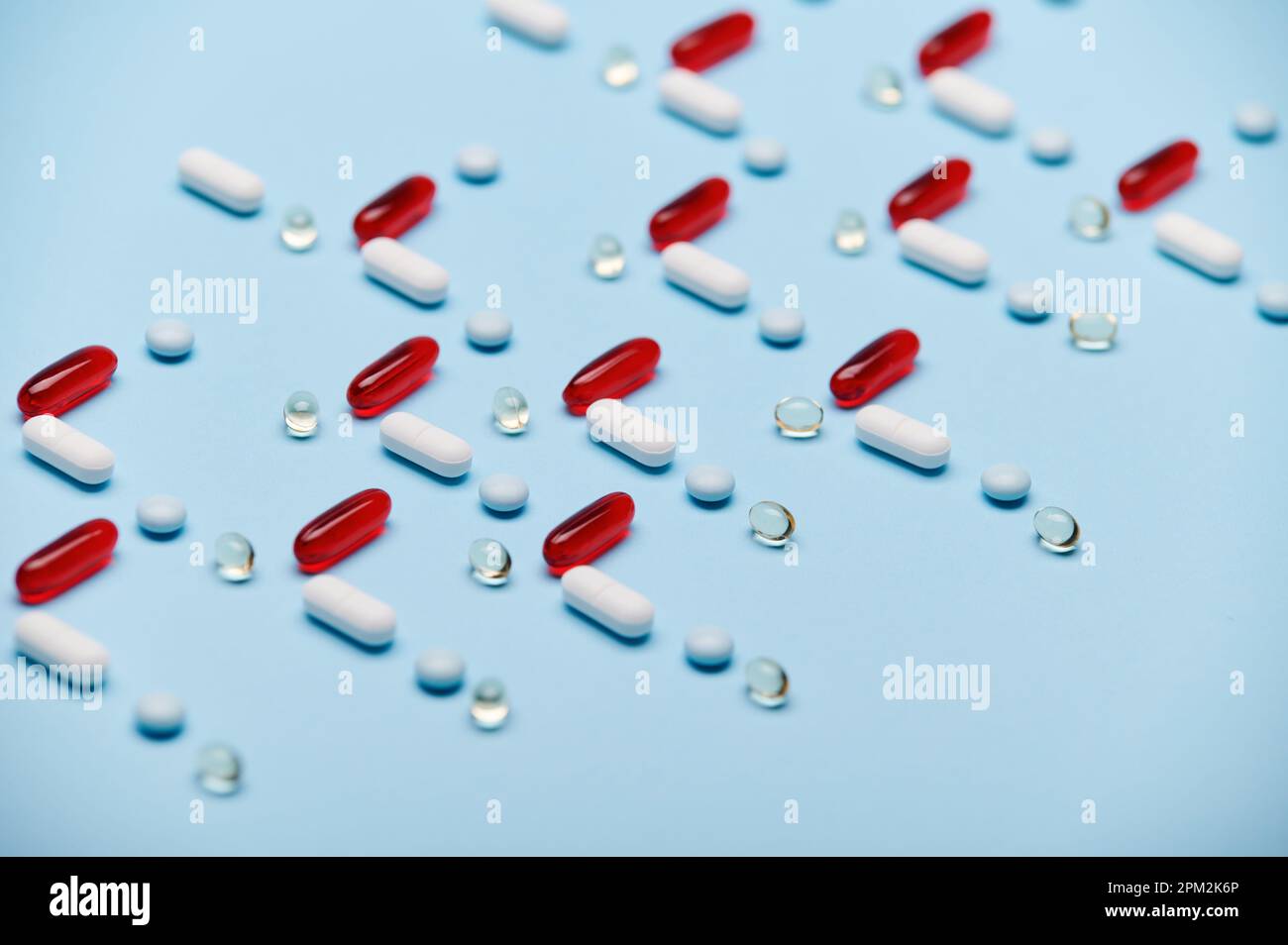 Layout with red gelatin translucent capsules and pharmaceutical pills ...