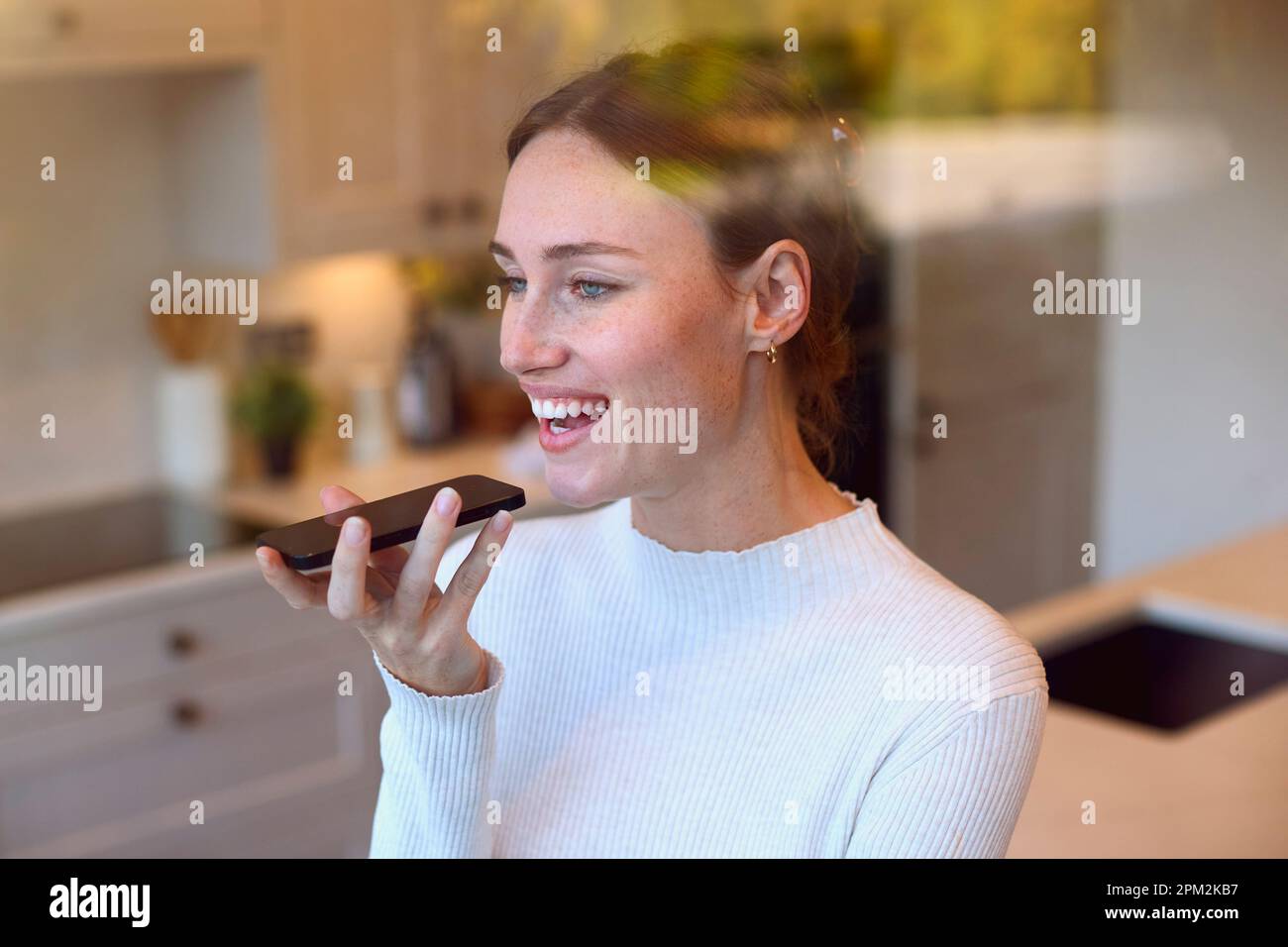 Woman Relaxing At Home In Kitchen Talking Into Microphone On Mobile ...